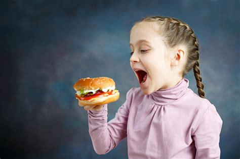예쁜 어린 소녀와 함께 즐기는 맛 있는 햄버거의 배고픈 순간을 행복 사소한 소녀 햄버거를 먹는 패스트 푸드이미지를 다음 개념에