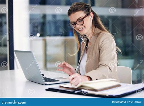 Shes A Busy Bee As Always A Young Businesswoman Wearing Earphones While Writing Notes And