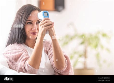 Woman Self Measuring Temperature With An Infrared Digital Thermometer On Her Forehead Stock
