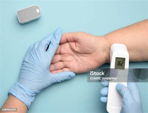 파란색 라텍스 장갑을 낀 의사가 전자 비접촉식 가젯으로 온도를 측정합니다 감지기에 대한 스톡 사진 및 기타 이미지 감지기 건강 진단 건강관리와 의술 Istock