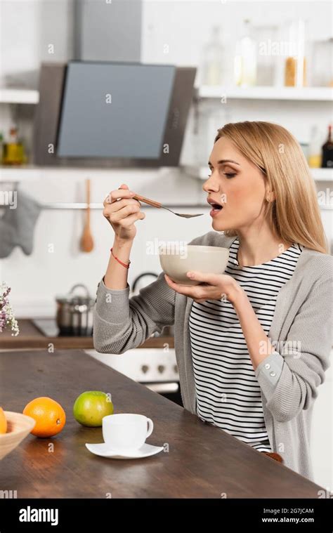 Blonde Woman Eating Breakfast In Kitchen Stock Photo Alamy