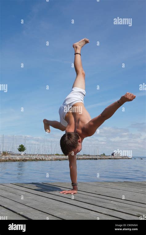 Teenager Doing An Acrobatic One Arm Handstand On A Jetty At The Beach