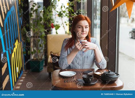 Молодая привлекательная женщина наслаждаясь чашкой кофе в кафе Стоковое Фото изображение