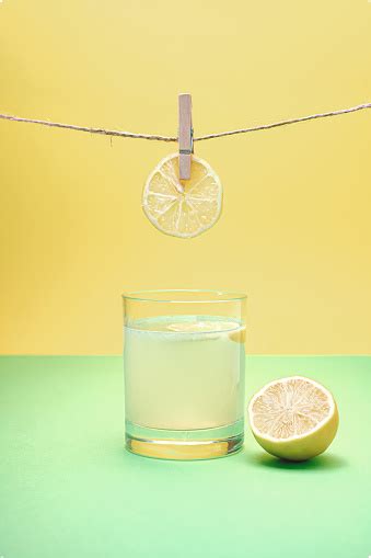 리무네이드가 있는 유리의 최소 구성과 파스텔 노란색과 녹색 배경에 빨래집게가 달린 밧줄에 레몬 조각이 매달려 있습니다 가득 찬에 대한 스톡 사진 및 기타 이미지 Istock