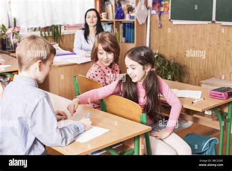 Cute School Girl Helping Her Classmate During Lesson Stock Photo Alamy