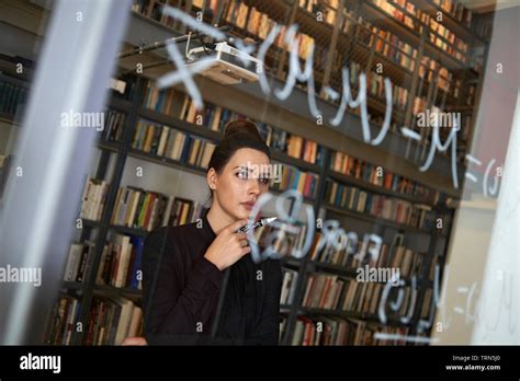 Female Computer Coder Writing Down A Complex Code On A Window At Her
