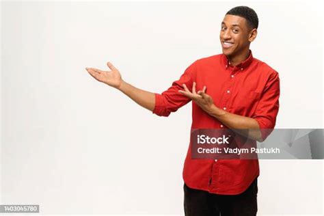 빨간 셔츠를 입은 잘 생긴 아프리카 계 미국인 청년은 손바닥을 옆으로 가리켜 흰색에 고립되어 있습니다 남자에 대한 스톡 사진 및 기타 이미지 Istock