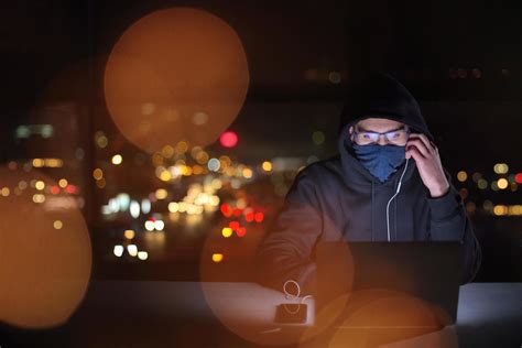 hacker using laptop computer while working in dark office 12442556