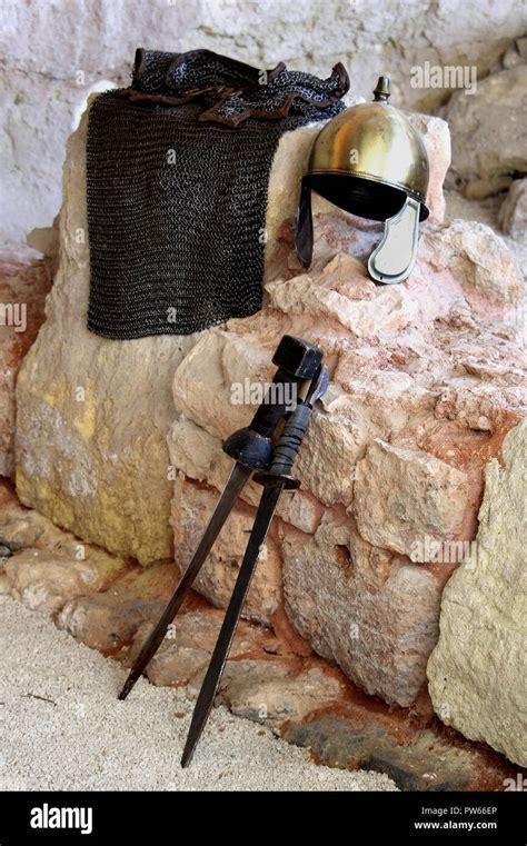 Roman Brass Helmet Armoured Tunic And Two Short Swords Leaning On A