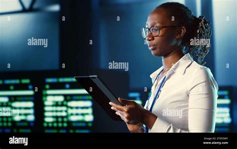 African American Woman Walking Through Server Farm Rows Providing Processing Resources For