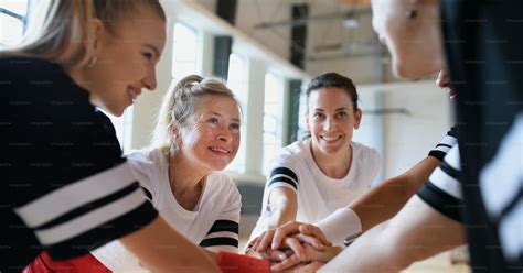 체육관에서 젊은 여성과 노인 여성이 손을 모으고 스포츠 팀 선수 체육관에서 승리를 축하하는 젊은이와 노인 여성 그룹 스포츠