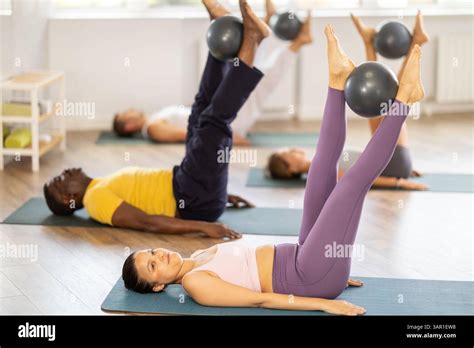 Asian Woman Doing Crescent Moon Exercise With Pilates Ball At Group