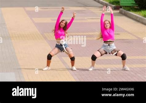 Two Cheerful Young Girls In Short Shorts Dancing Dancehall With Twerking Elements Outdoors On A