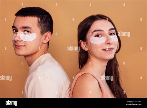 A Smiling Teenage Couple With Moisturizing Patches Under Their Eyes A