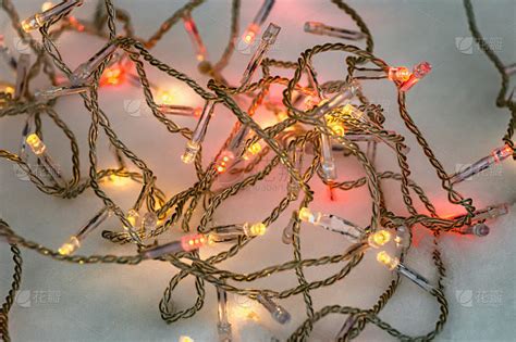 美丽的红色和黄色的led灯花环燃烧的五颜六色的灯在雪地的背景在假日晚上