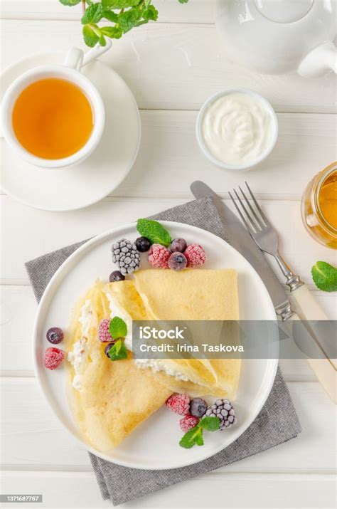 전통적인 얇은 팬케이크 또는 크레페와 코티지 치즈 건포도 열매 꿀 사워 크림이 흰색 나무 배경에 있습니다 마레그나에 대한 음식 공간을 복사합니다 0명에 대한 스톡 사진 및