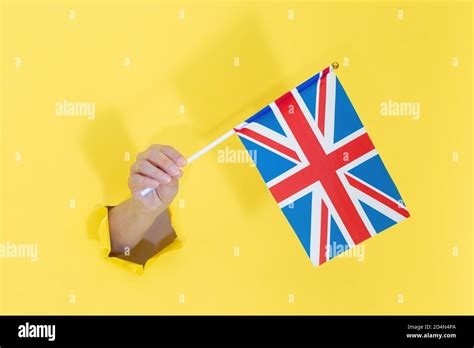 Hand Holding English Flag From Yellow Torn Paper United Kingdom Flag