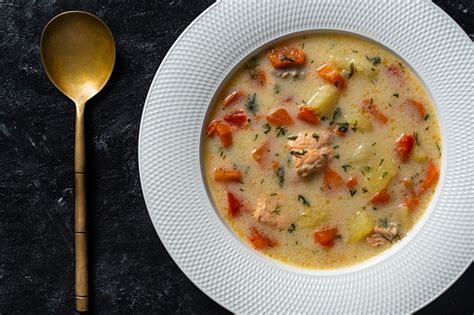 당근 감자 토마토 고추를 곁들인 신선한 연어 생선 수프는 검은 배경에 흰색 접시에 담겨 있습니다 맛있는 저녁 식사는 연어와 크림 생선 수프로 구성됩니다 상위 뷰 가공 치즈에