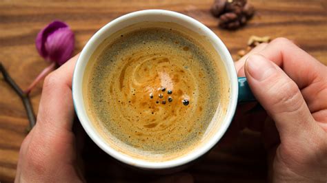 여성의 손은 향기로운 커피와 컵을 개최 나무 탁자 위에는 향기로운 커피 한 잔이 서 있습니다 맛있는 우유 거품으로 상쾌한 커피 가정 생활에 대한 스톡 사진 및 기타 이미지