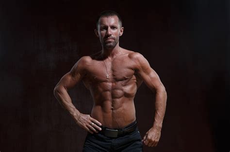 Hombre atlético delgado con un torso musculoso desnudo aislado en un fondo oscuro Foto Premium