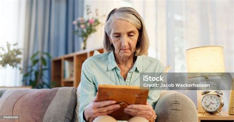슬프고 노인 여성과 액자는 향수 기억 및 가정 거실에서 역사를 기억합니다 은퇴 슬픔에 잠긴 실종자 소파에서 외롭고 애도하는 가족의 사진 및 과거 가정 생활에 대한 스톡 사진
