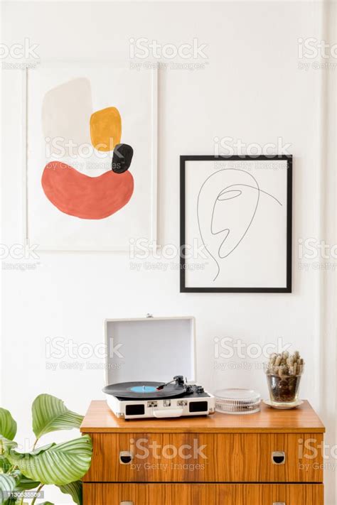 디자인 Commode와 거실의 빈티지 복고 인테리어 비닐 레코더 선인장과 흰색 벽에 포스터를 모의 갈색 나무 마루와 식물이 있는