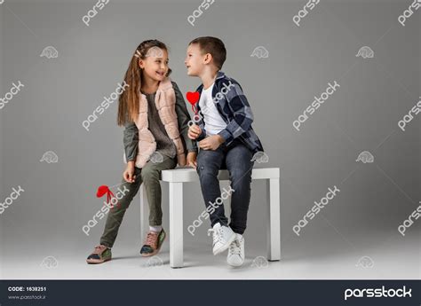 دختر و پسر بچه دختر و پسر بچه شیک و خندان با قلب های قرمز روی چوب با