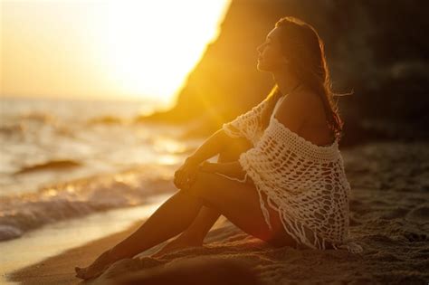 Free Photo Young Relaxed Woman Sitting On Sand And Enjoying In Sunset