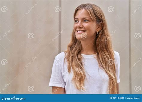 Jovencita Rubia Sonriendo Confiada Mirando Al Costado Sobre Fondo