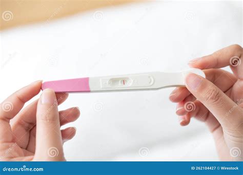 Closeup Of A Womanand X27s Hand Holding Up A Pregnancy Test Kit With A