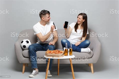 웃는 커플 여자 남자 축구 팬은 회색 배경에 고립 된 빈 빈 화면으로 휴대 전화를 들고 응원 하는 팀을 지원 합니다 사람들의