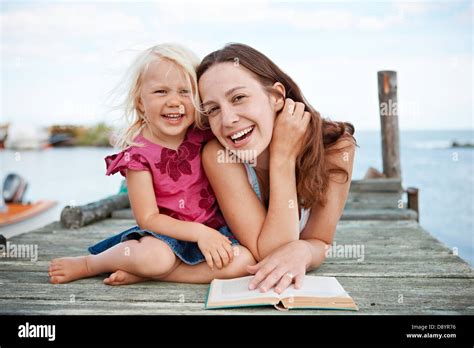 Mother And Daughter Resting On Jetty Smiling Portrait Stock Photo Alamy