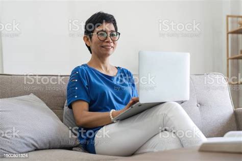 집에서 일하는 행복한 성공적인 성숙한 비즈니스 여성 노인 노트북을 들고 카메라를 보고 웃고 안락의자에서 쉬고 현대 기술을