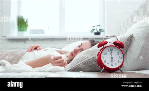 Portrait Of A Pretty Female Sleeps In The Bed Alarm Clock Is Ringing