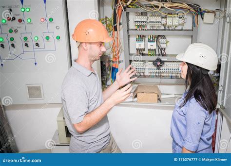 A Team Of Electricians Are Talking Near The Electrical Panel A Man And