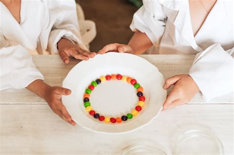 흰색 유니폼을 입은 어린이들은 가정 실험실에서 색과자와 물로 과학 실험을 실시합니다 접시에 무지개의 모양 학교 개념으로 돌아가기 2명에 대한 스톡 사진 및 기타 이미지