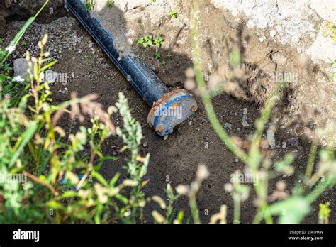 Closed End Of A Plastic Water Pipe Lying Along A Ditch With High