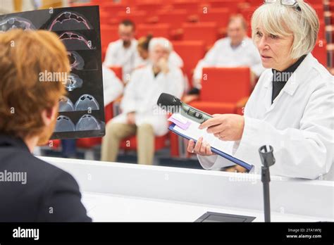Female Professional Asking Question To Speaker While Holding X Ray During Medical Conference