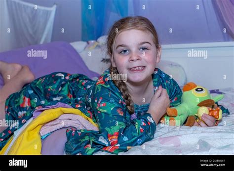 Smiling Six Year Old Girl Missing Front Teeth Lying On Her Bed With Her