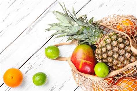 회색 배경에 다양한 열대 과일이있는 친환경 쇼핑 백 파인애플 망고 키위 오렌지 등 맨 위 보기입니다 지속 가능한 라이프 스타일 플라스틱이 없습니다 제로 폐기물 개념 가방에