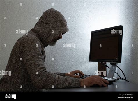 Bearded Man With A Hoodie Hacking On A Black Screen Computer Stock