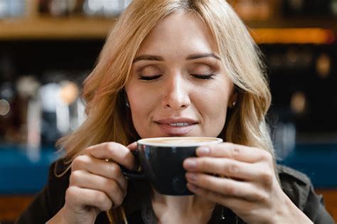 레스토랑 카페에서 아침 식사 워크 브레이크 브런치를하면서 냄새가 나는 따뜻한 음료 커피 차의 향기를 즐기는 예쁜 백인 젊은 여성