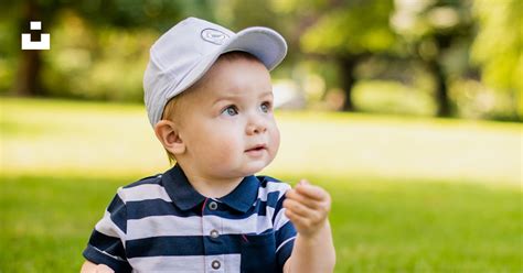 파란색과 흰색 스트라이프 폴로 셔츠와 푸른 데님 반바지를 입은 소년이 푸른 잔디에 앉아 있다 사진 Unsplash의 무료 하노버 이미지