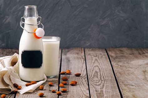 유리 및 회색 배경에 나무 테이블에 아몬드 견과류의 비 건 식물 우유 병 복사 공간이 있는 배너입니다 유제품 무료 우유 대체 음료와 재료 개념 0명에 대한 스톡 사진 및