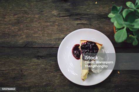 나무 테이블에 흰색 접시에 검은 건포도와 블루 베리 소스와 수제 치즈 케이크의 맛있는 조각디저트신선한 유기농 민트와 함께 달콤한 여름 페이스트리 거품 내기에 대한 스톡 사진