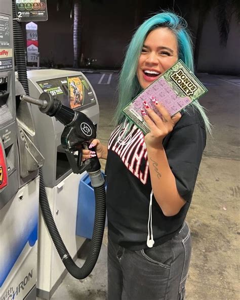 A Woman With Blue Hair Is Pumping Gas Into Her Car At A Gas Station And Smiling