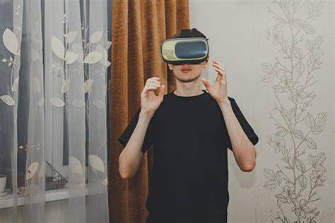 Vr 헬멧을 쓰고 있는 청년이 집 내부의 가상 현실에서 물체와 상호 작용합니다 20 24세에 대한 스톡 사진 및 기타 이미지 20 24세 3차원 형태 가상현실
