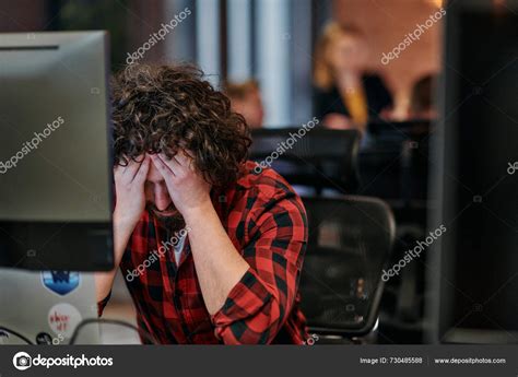frustrated programmer messy hair sits staring his computer monitor look