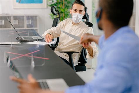 보호용 얼굴 마스크를 쓰고 재채기 경비원으로 사무실 책상을 분리하면서 사무실에서 함께 일하는 두 명의 사업가 2명에 대한 스톡 사진 및 기타 이미지 Istock