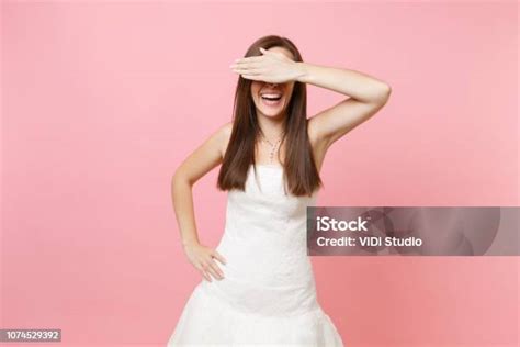 파스텔 핑크 배경에 고립 손으로 덮고 눈을 숨기고 아름 다운 레이스 화이트 웨딩 드레스 신부 여자 웃음의 초상화 결혼식 축 하 개념입니다 광고에 대 한 공간을 복사 합니다